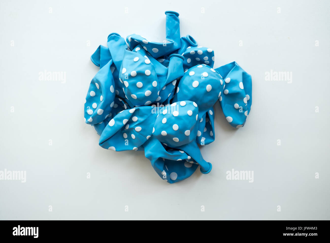 Deflated blue pastel with white dots rubber air balloon isolated over ...