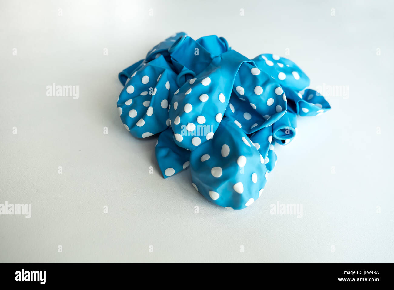 Deflated blue pastel with white dots rubber air balloon isolated over ...