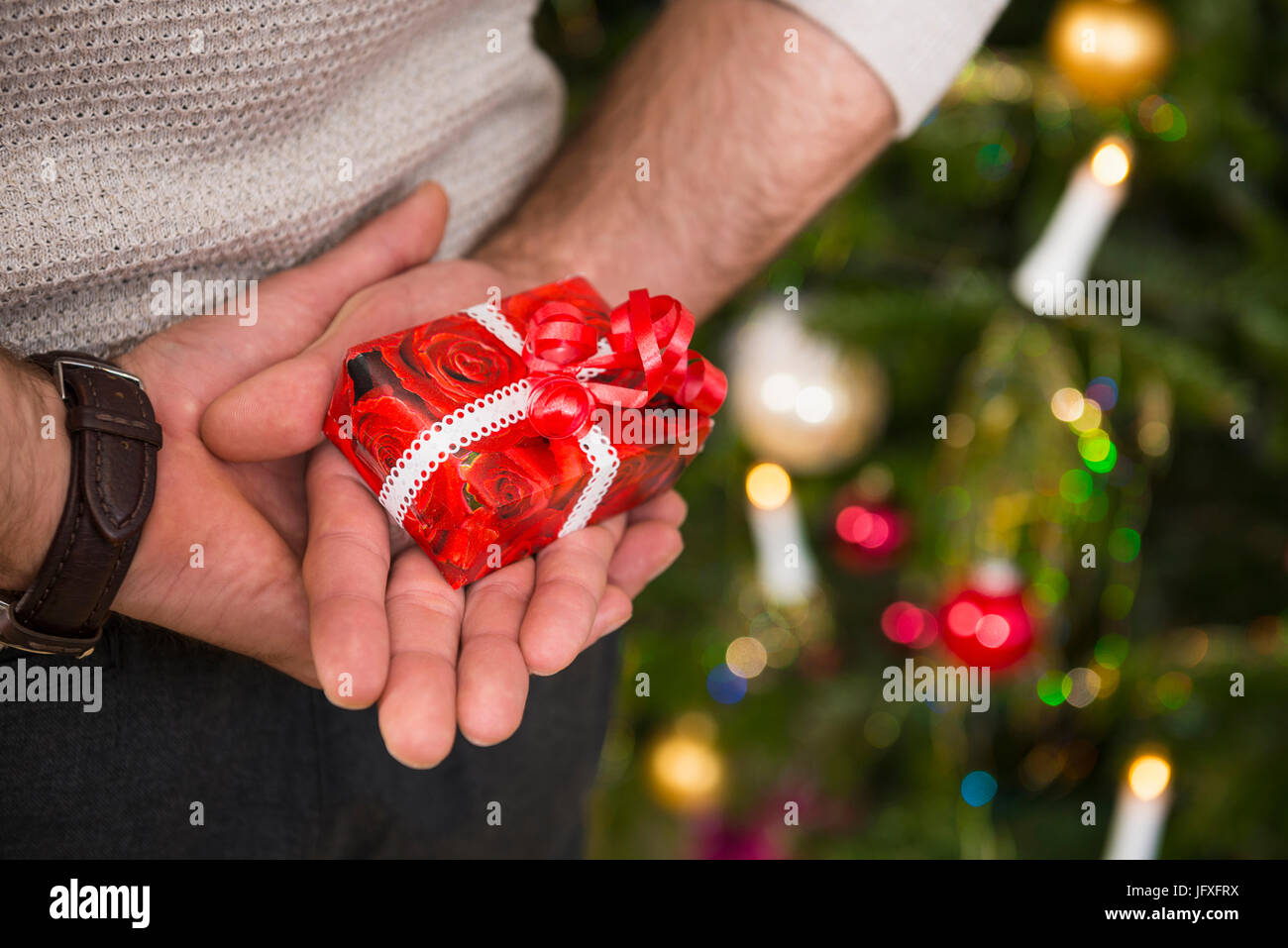 Man holding christmas present behind back Stock Photo - Alamy