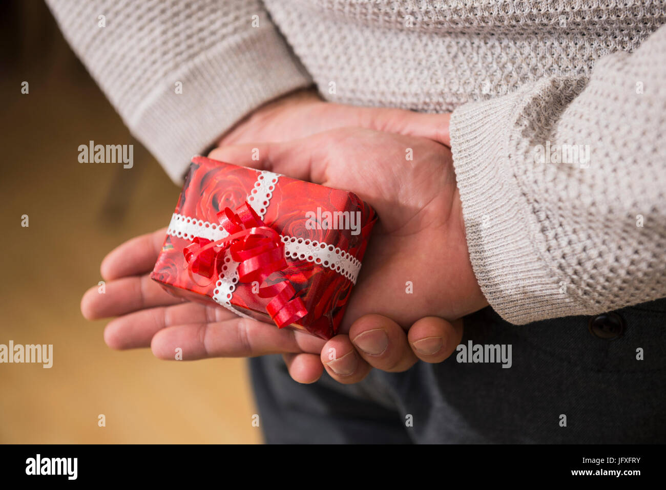 Man holding Christmas gift behind back Stock Photo - Alamy
