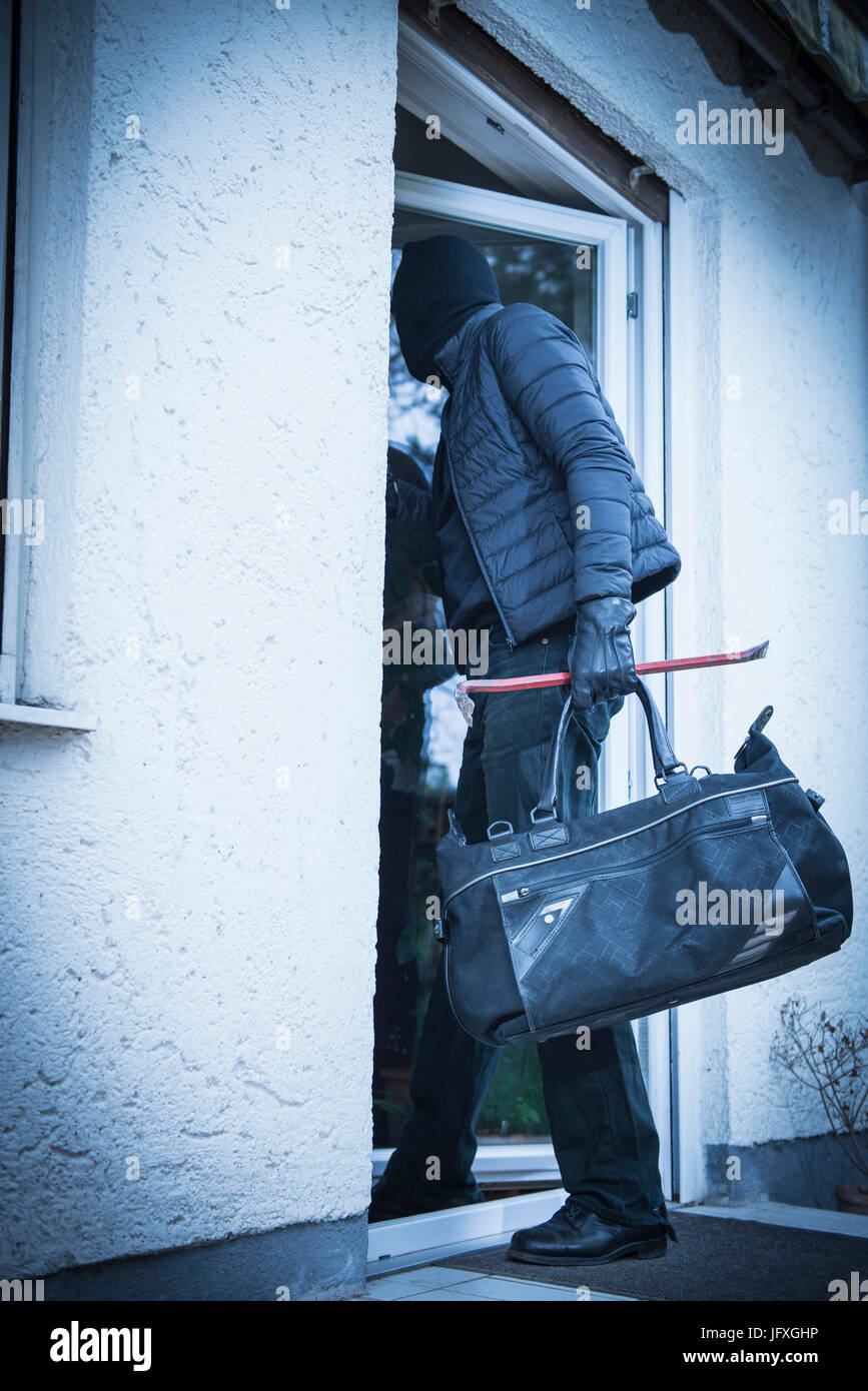 Burglar entering house with a crowbar and bag Stock Photo - Alamy