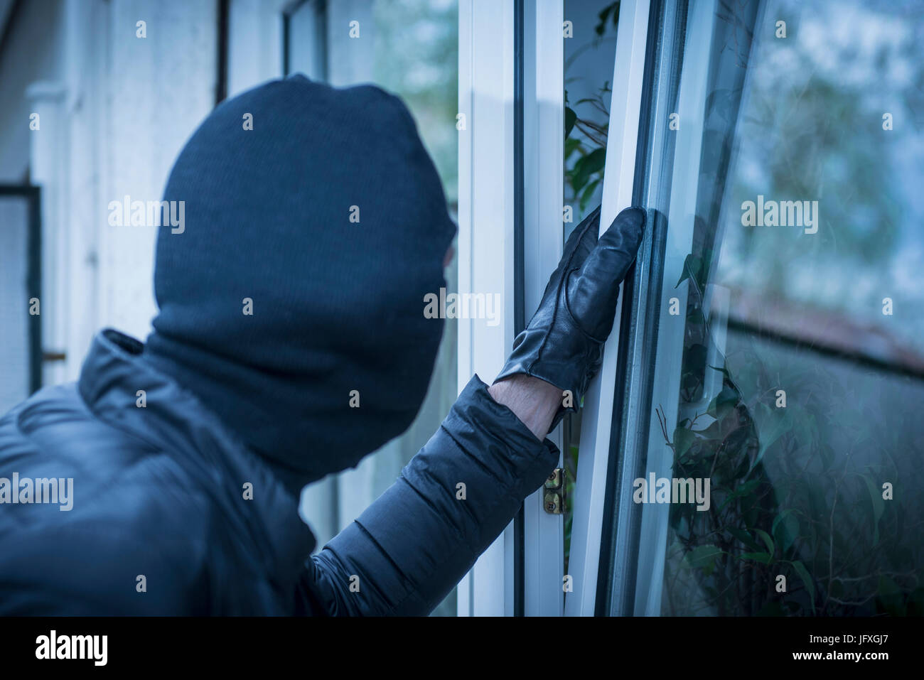 Burglar trying to open a window Stock Photo - Alamy