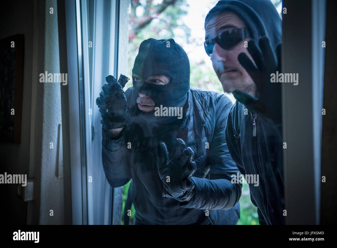 Two burglars peeking through glass door of house Stock Photo - Alamy