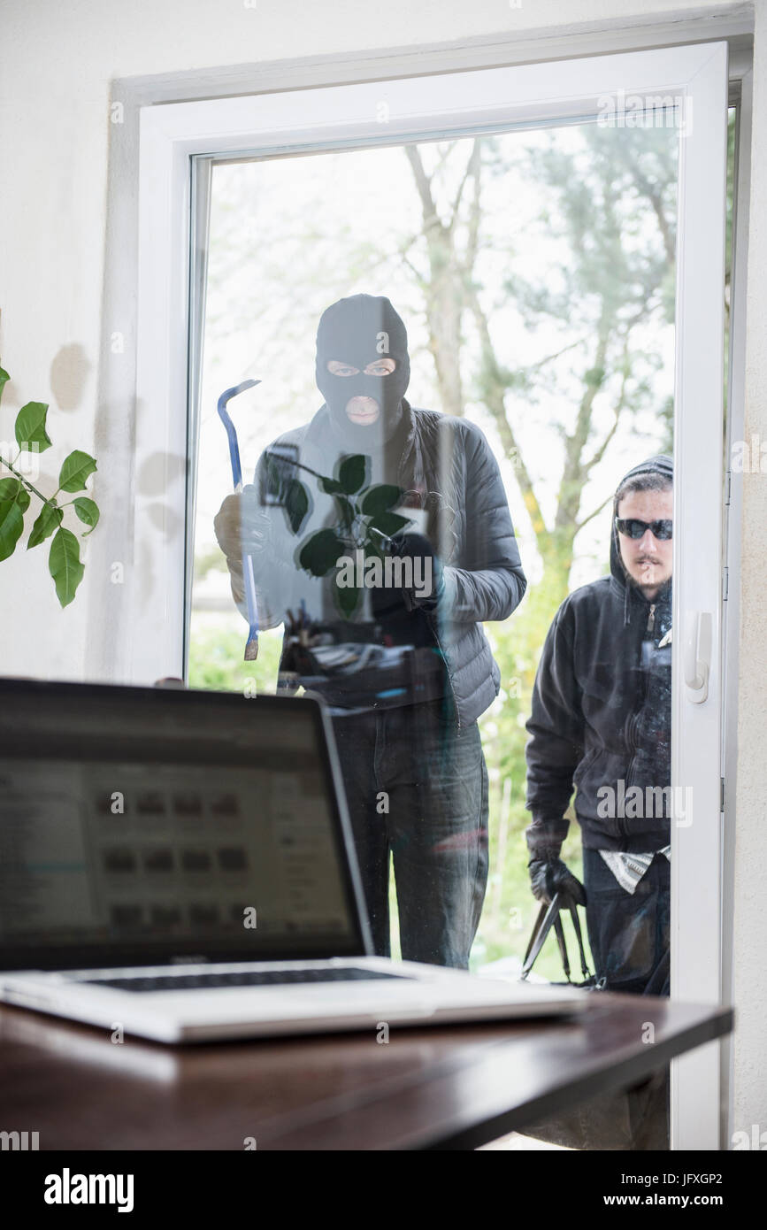 Burglar looking at laptop through window Stock Photo - Alamy