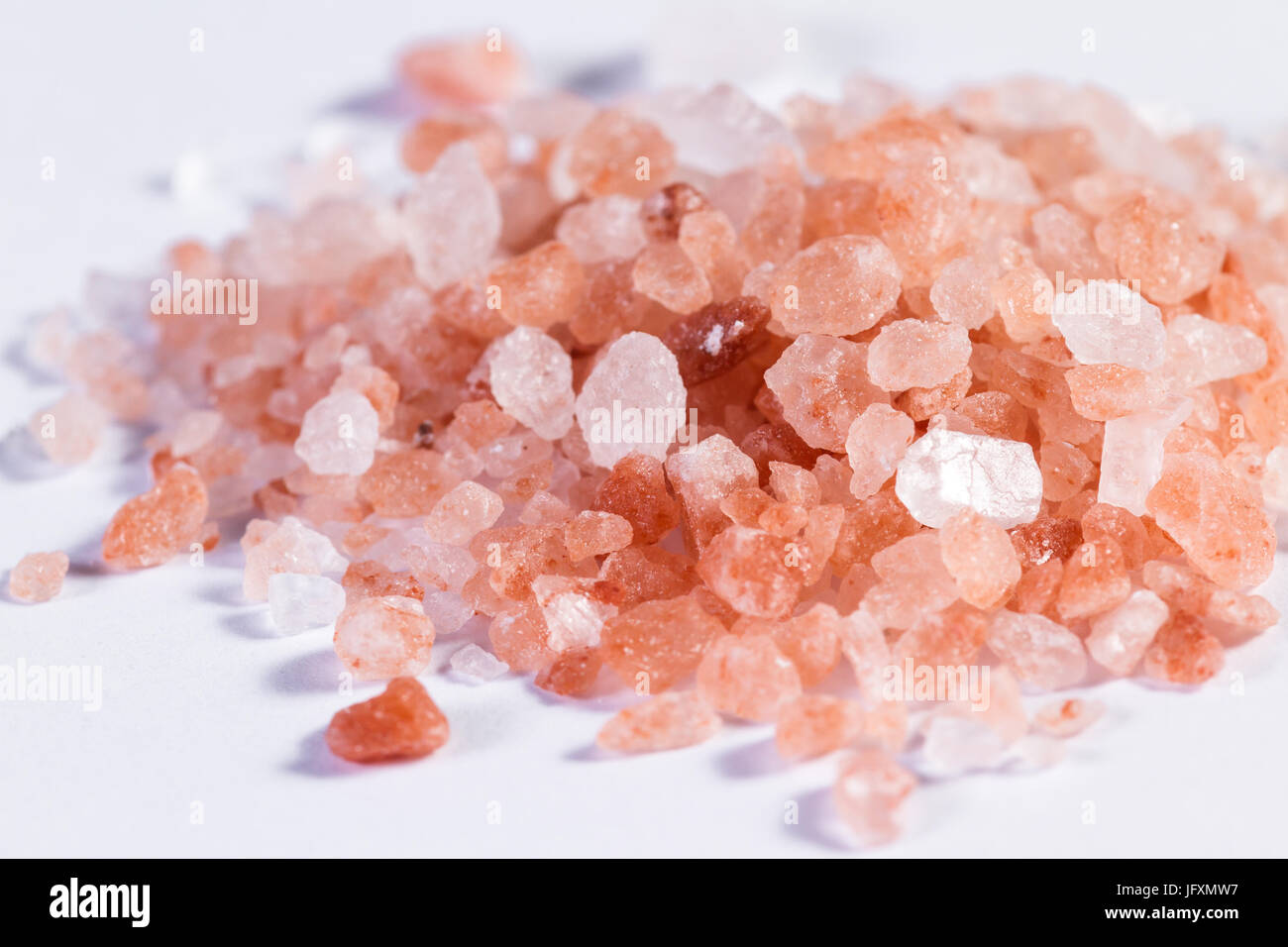 Himalayan pink salt crystals piled and isolated on a white background ...