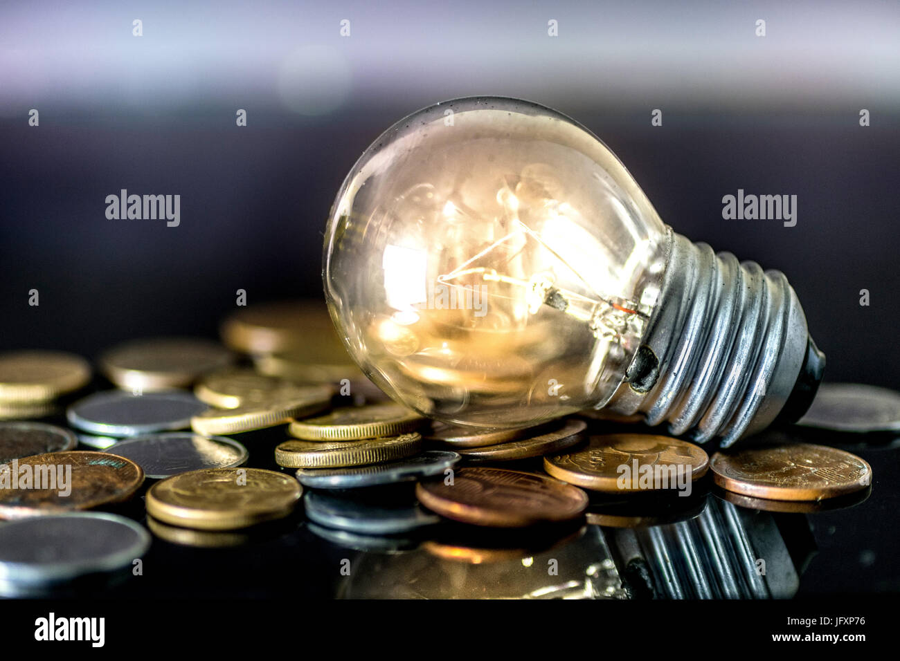 Yellow light bulb on over pile of coins - money, finance, savings ...
