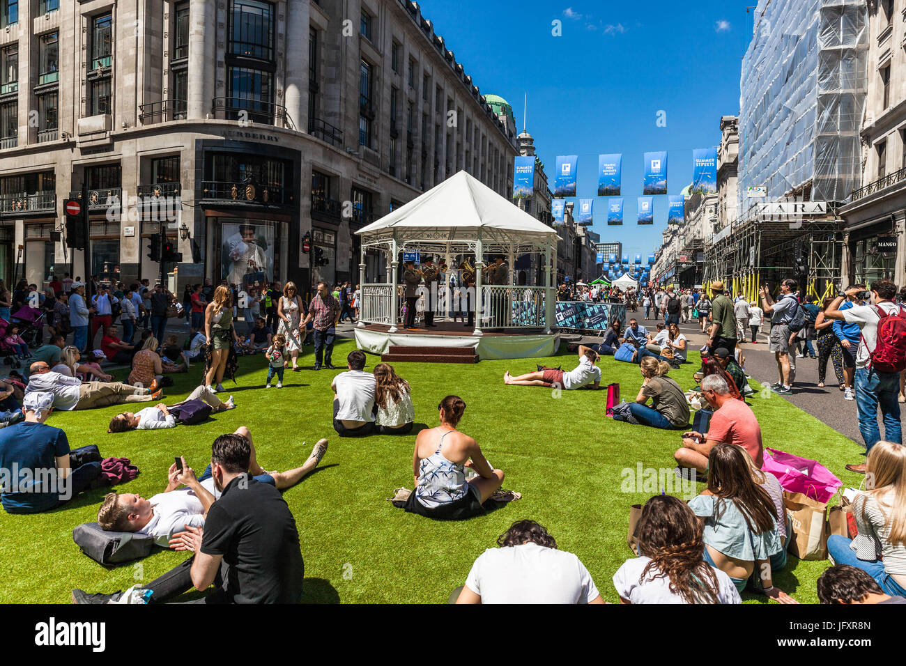 An audience sitting on artificial grass watching performance on ...