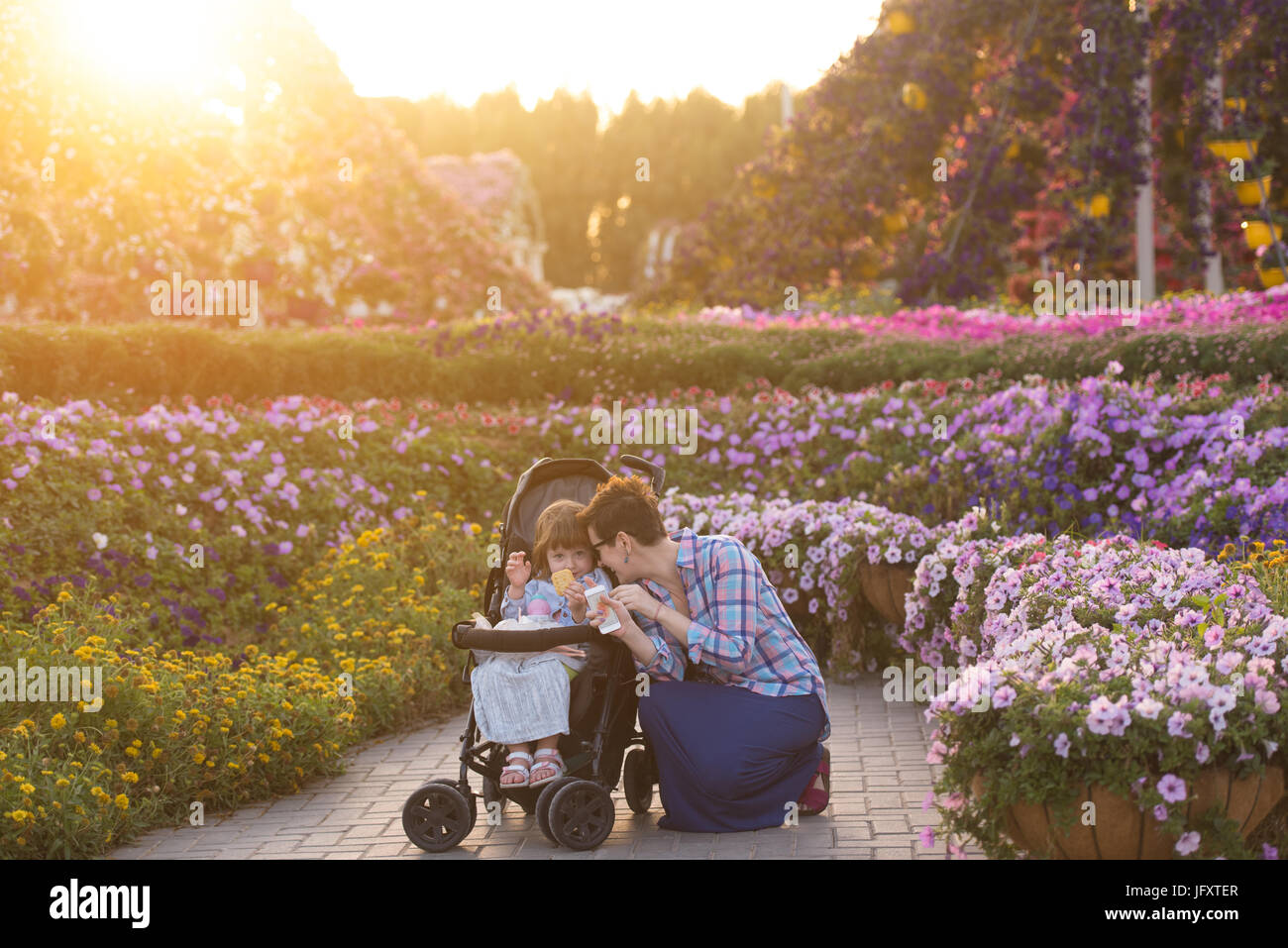young mother and cute little girl in a baby stroller enjoying a ...