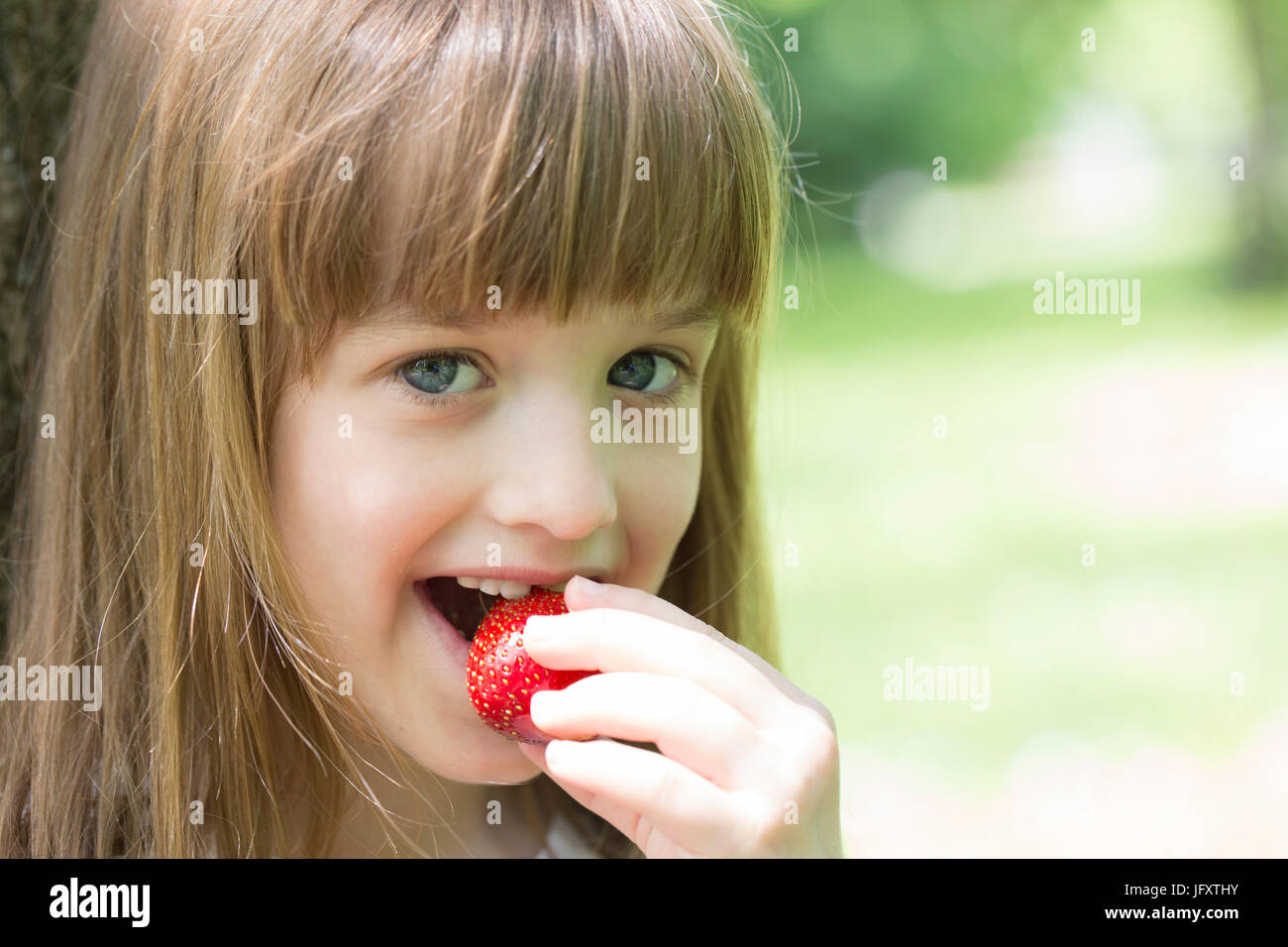 Little cute girl with a beautiful face enjoy while eating a juicy ...