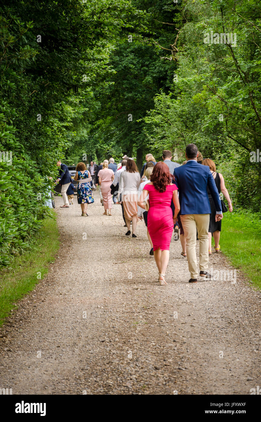 A party of wedding guests walking down a road towards the reception ...