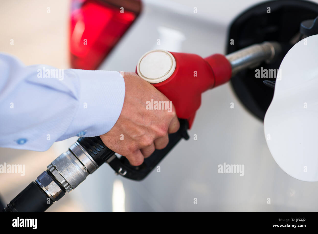 refueling gun is inserted into the tank of white car Stock Photo - Alamy