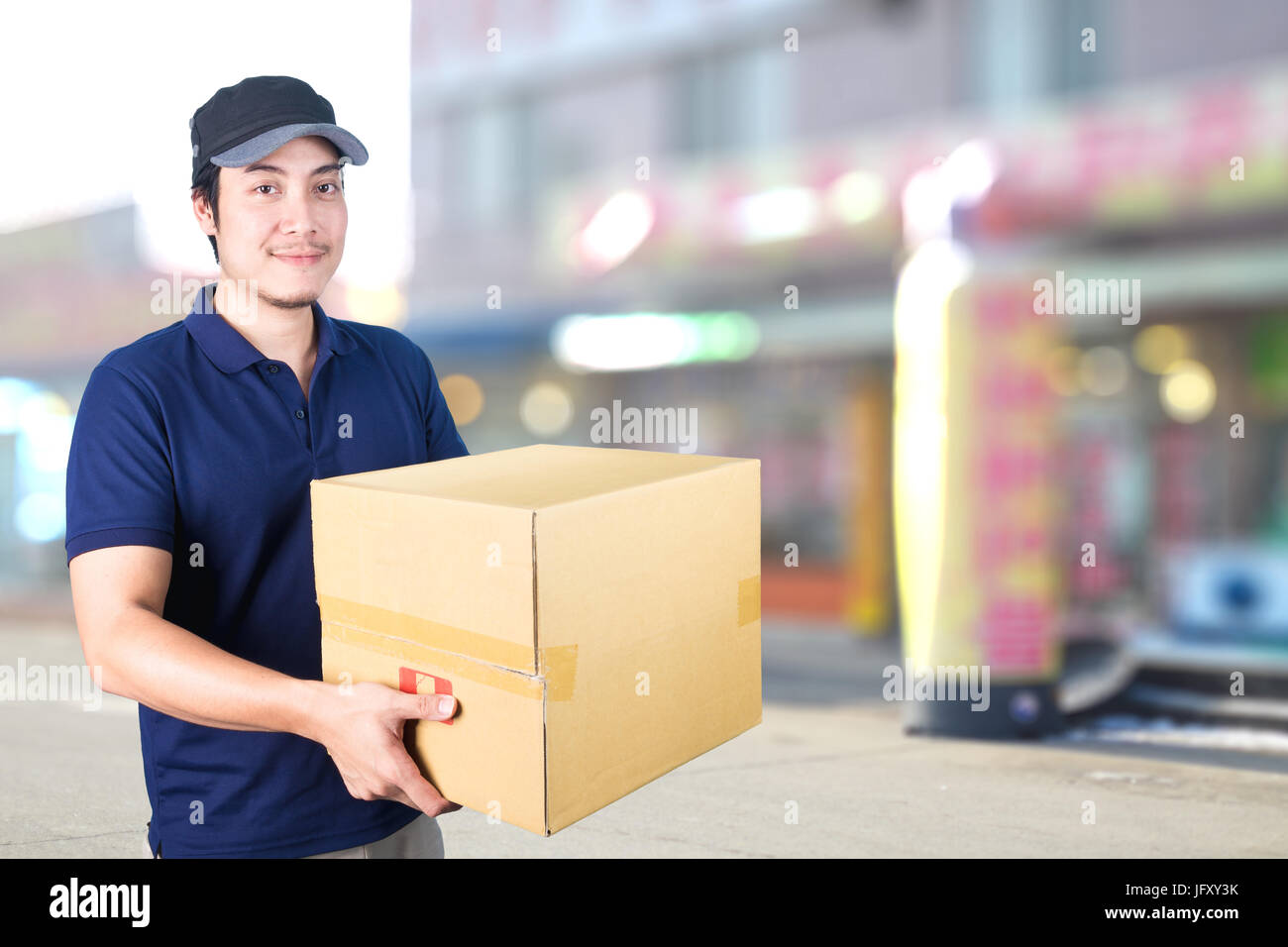 Asian smile Delivery man with cardboard box in hand standing on blurred ...