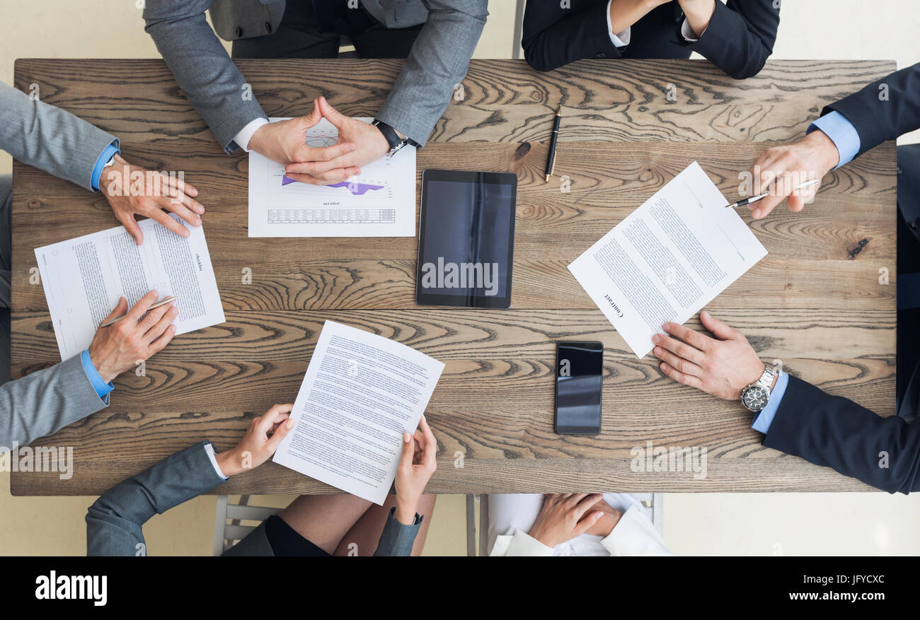 Top view of confident business men in suits sitting at wooden table and ...
