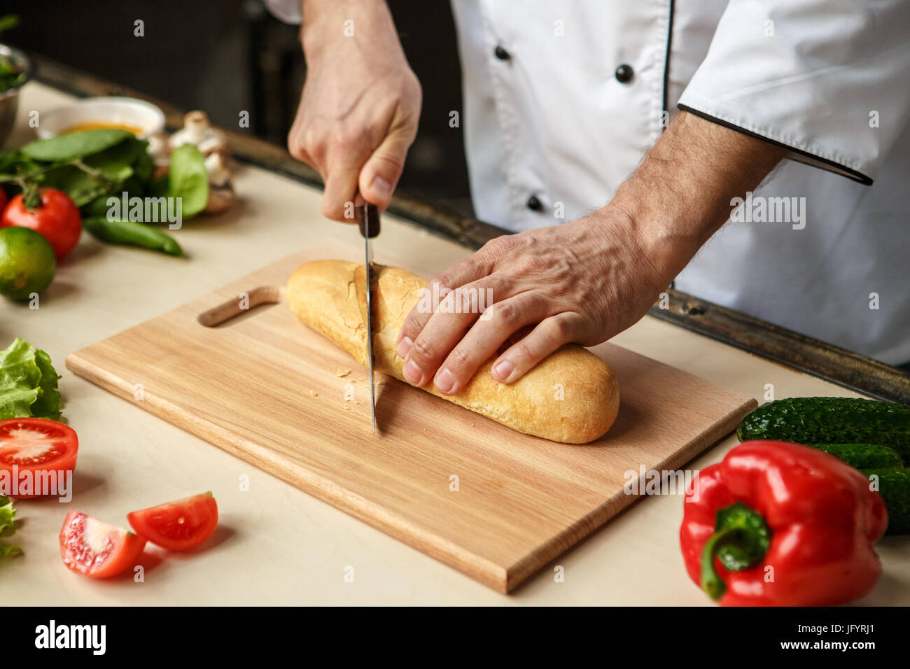 Mature male professional chef cooking meal indoors cutting ingredients ...