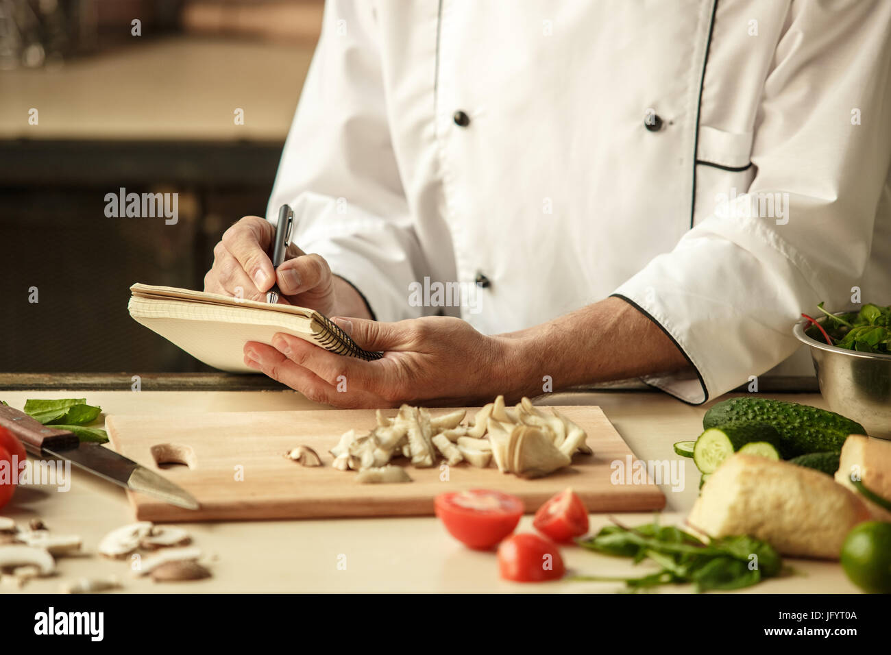 Mature male professional chef cooking meal indoors writing receipt ...