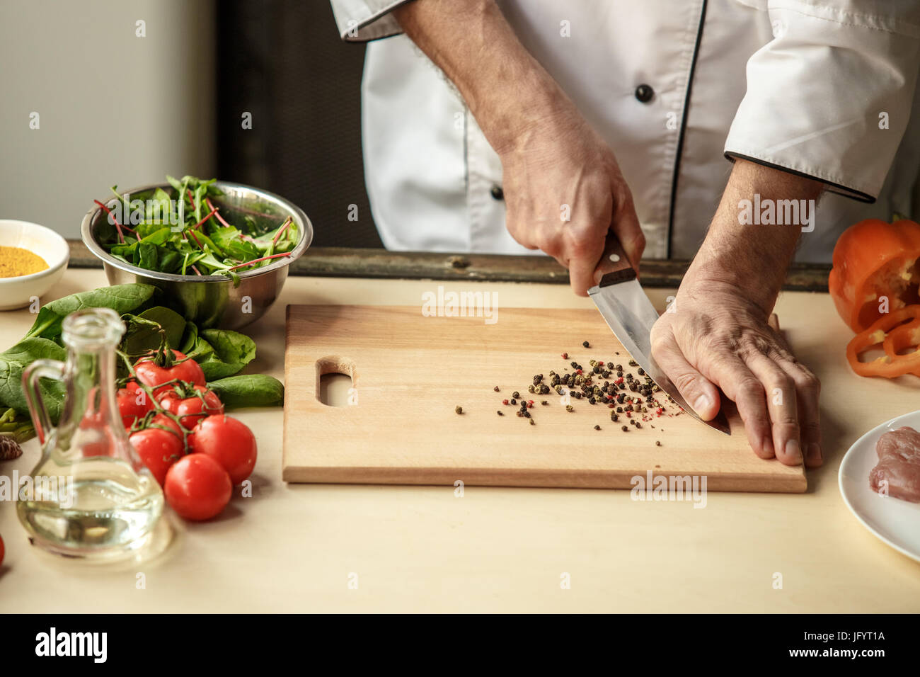 Mature male professional chef cooking meal indoors cutting ingredients ...