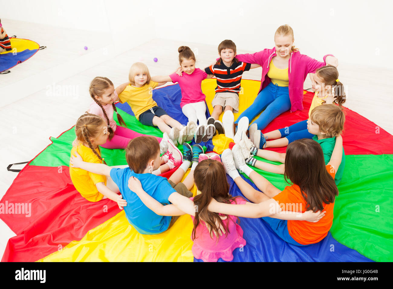 Big group of happy children sitting in a circle with nursery teacher ...