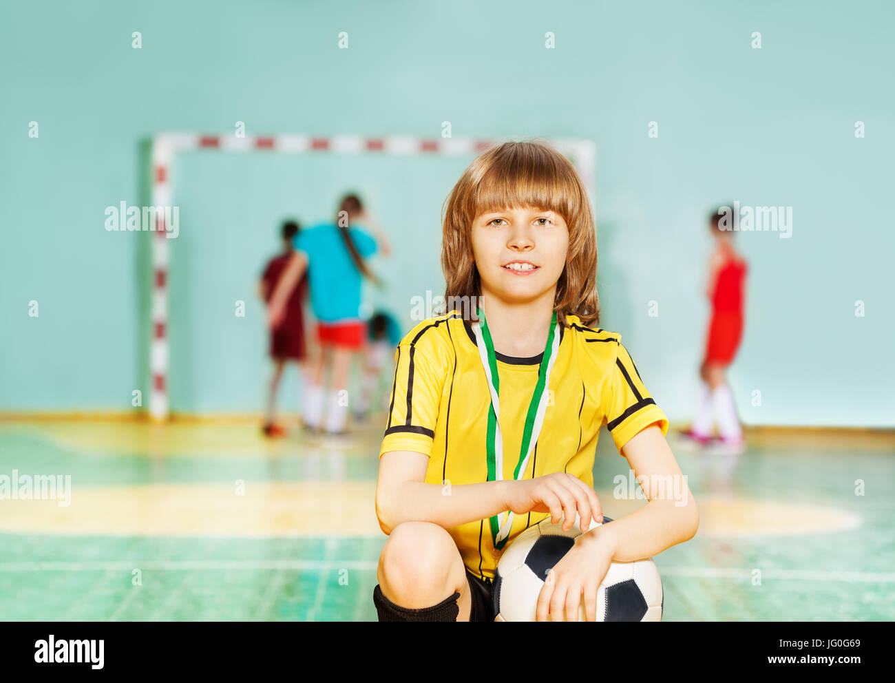 Close-up portrait of happy 12 years old boy, sitting with soccer ball ...