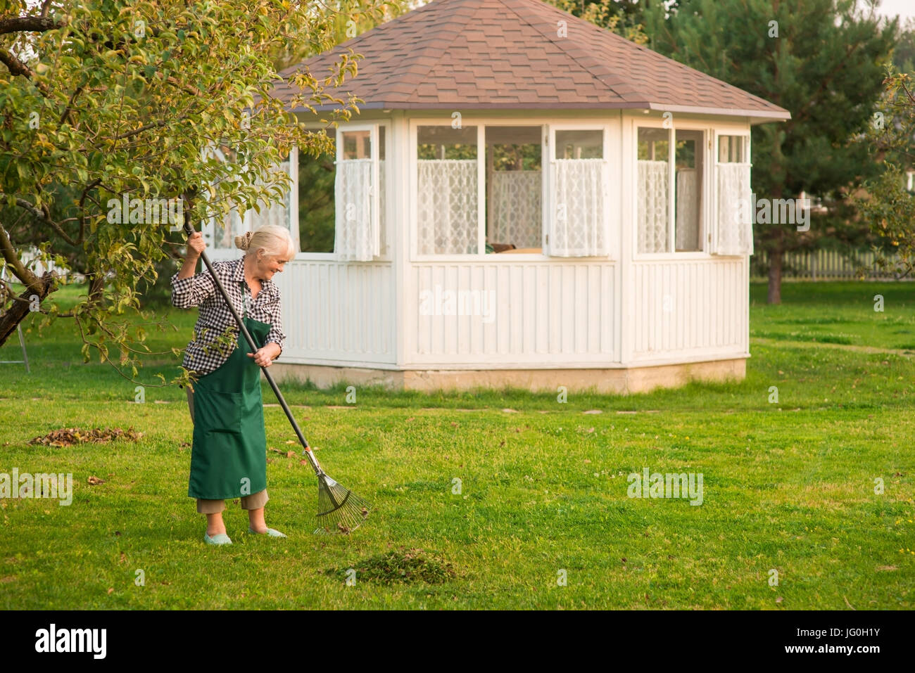 Senior woman with rake, garden Stock Photo - Alamy