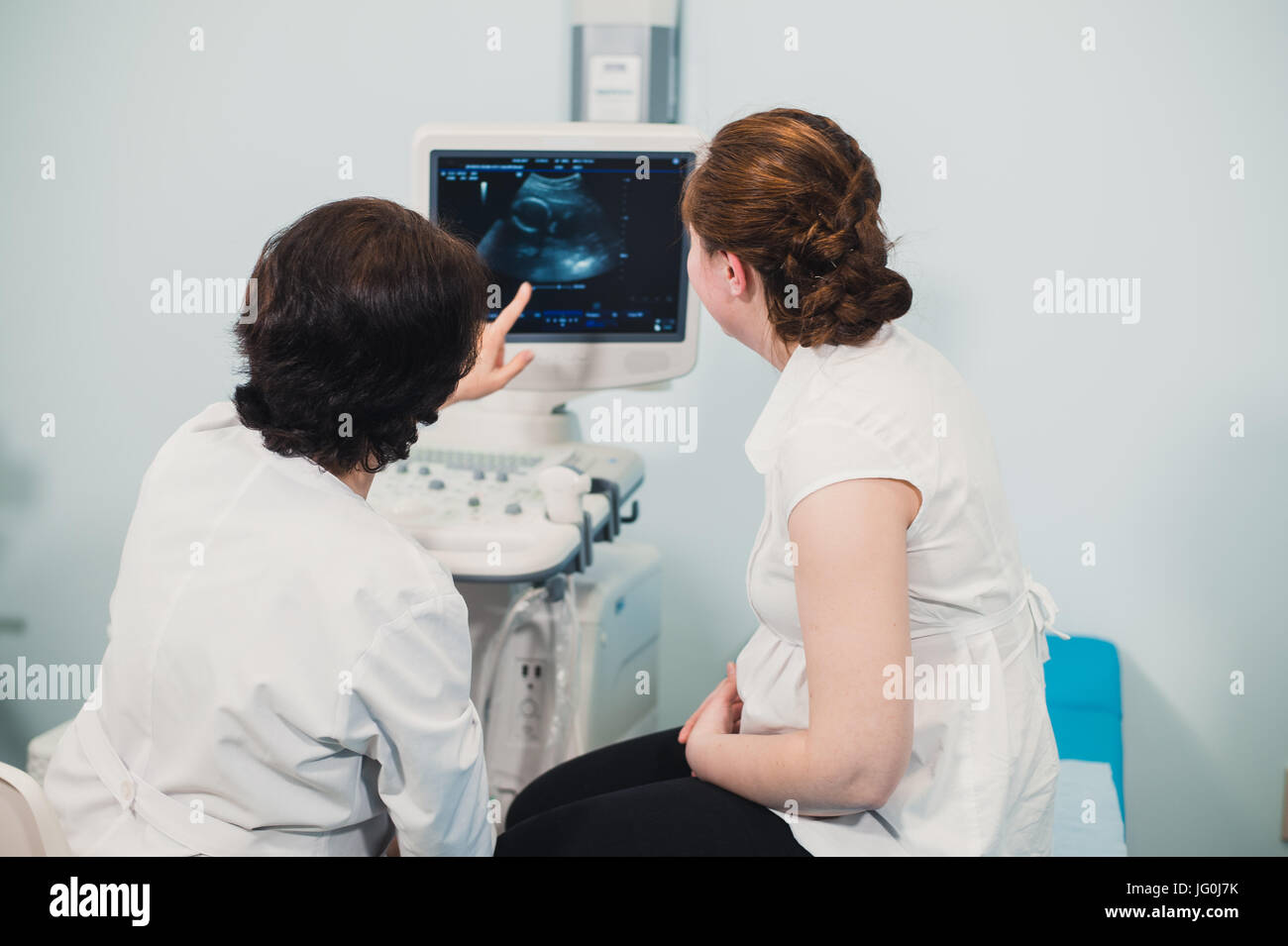 Doctor showing baby ultrasound image on computer to pregnant woman ...