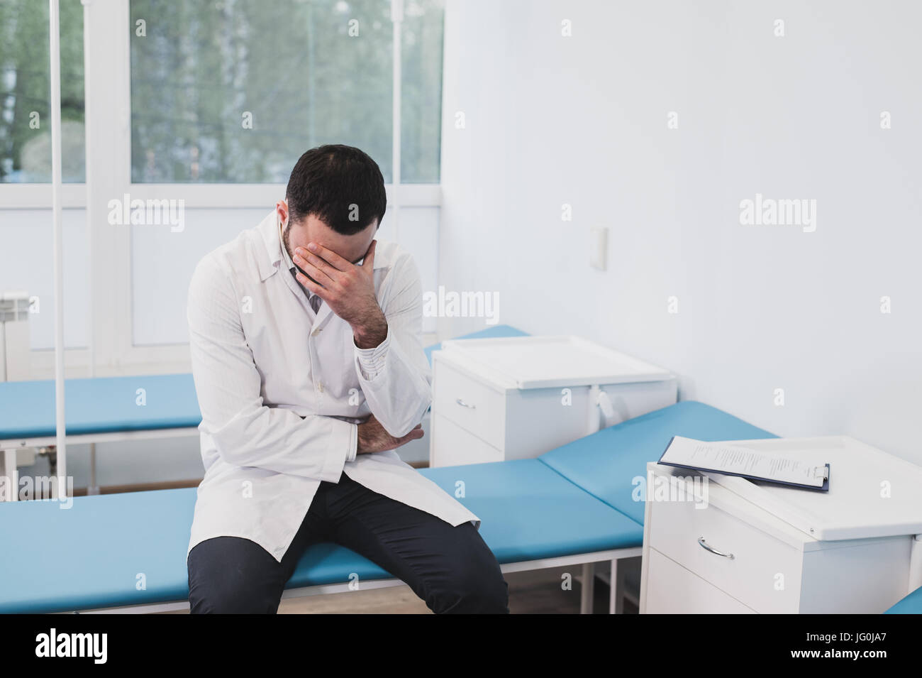 Tired doctor sitting alone in hospital ward Stock Photo - Alamy
