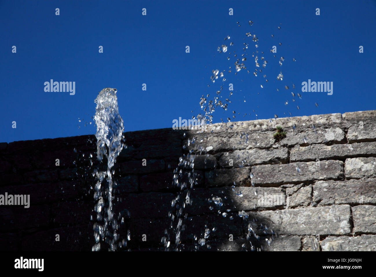 Splashes of water into the air on brick wall background Stock Photo - Alamy
