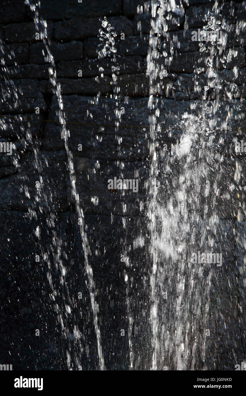 Splashes of water into the air on brick wall background Stock Photo - Alamy