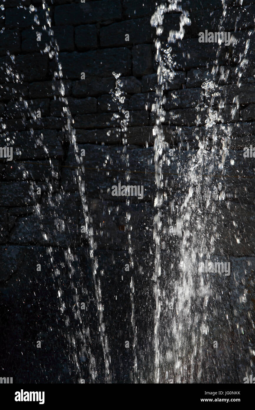 Splashes of water into the air on brick wall background Stock Photo - Alamy