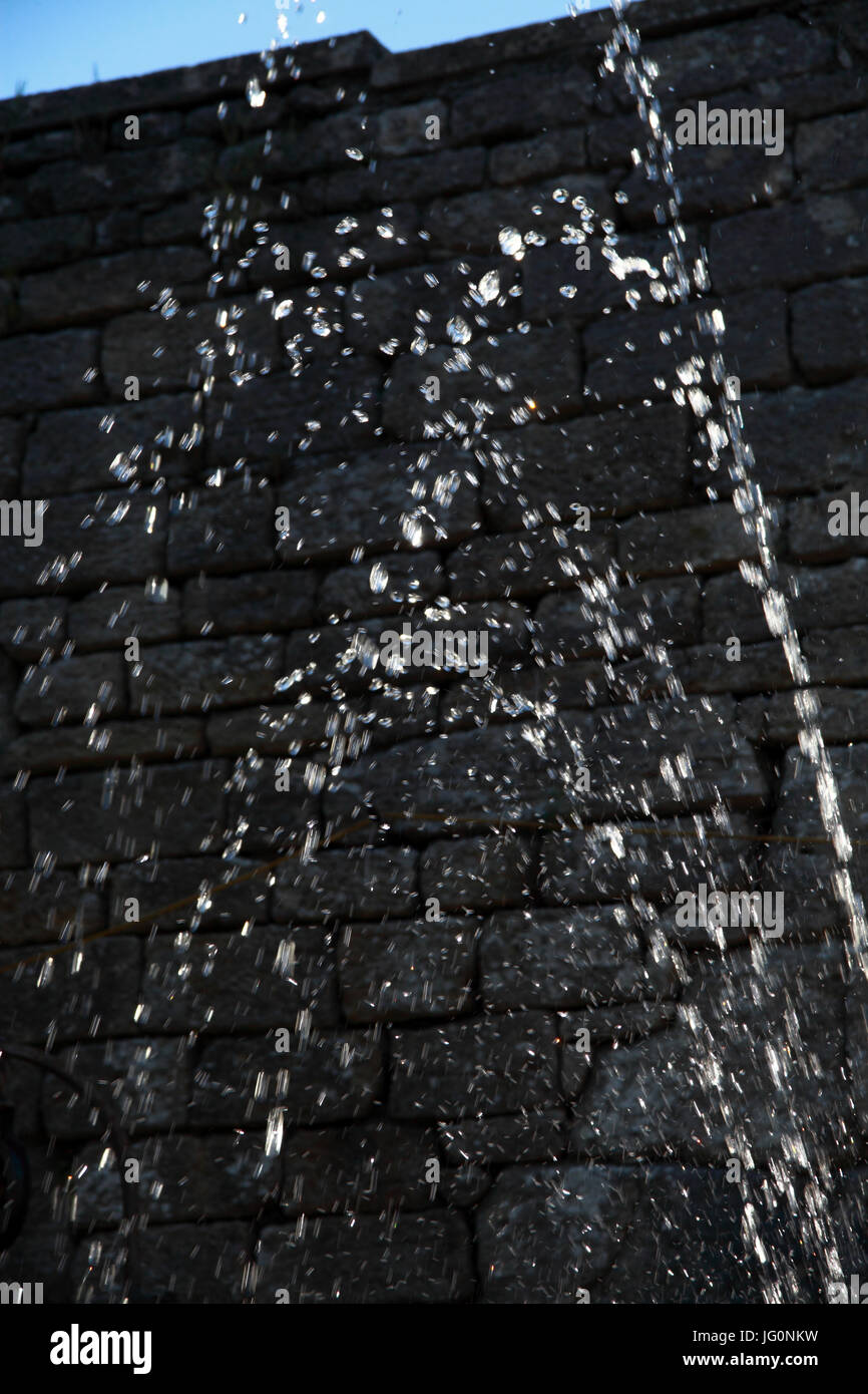Splashes of water into the air on brick wall background Stock Photo - Alamy