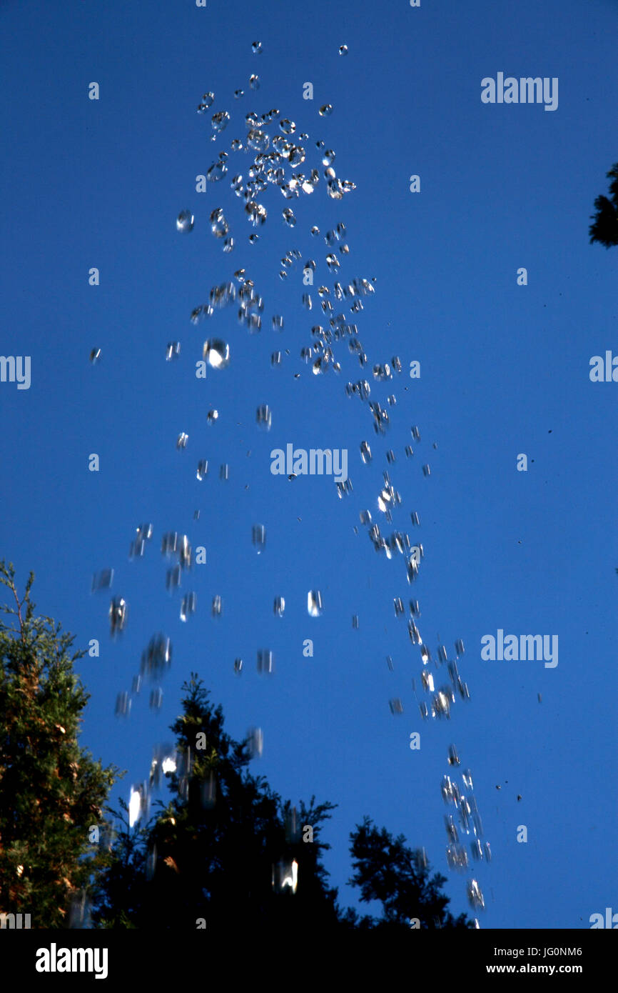 Splashes of water into the air on sky background Stock Photo - Alamy