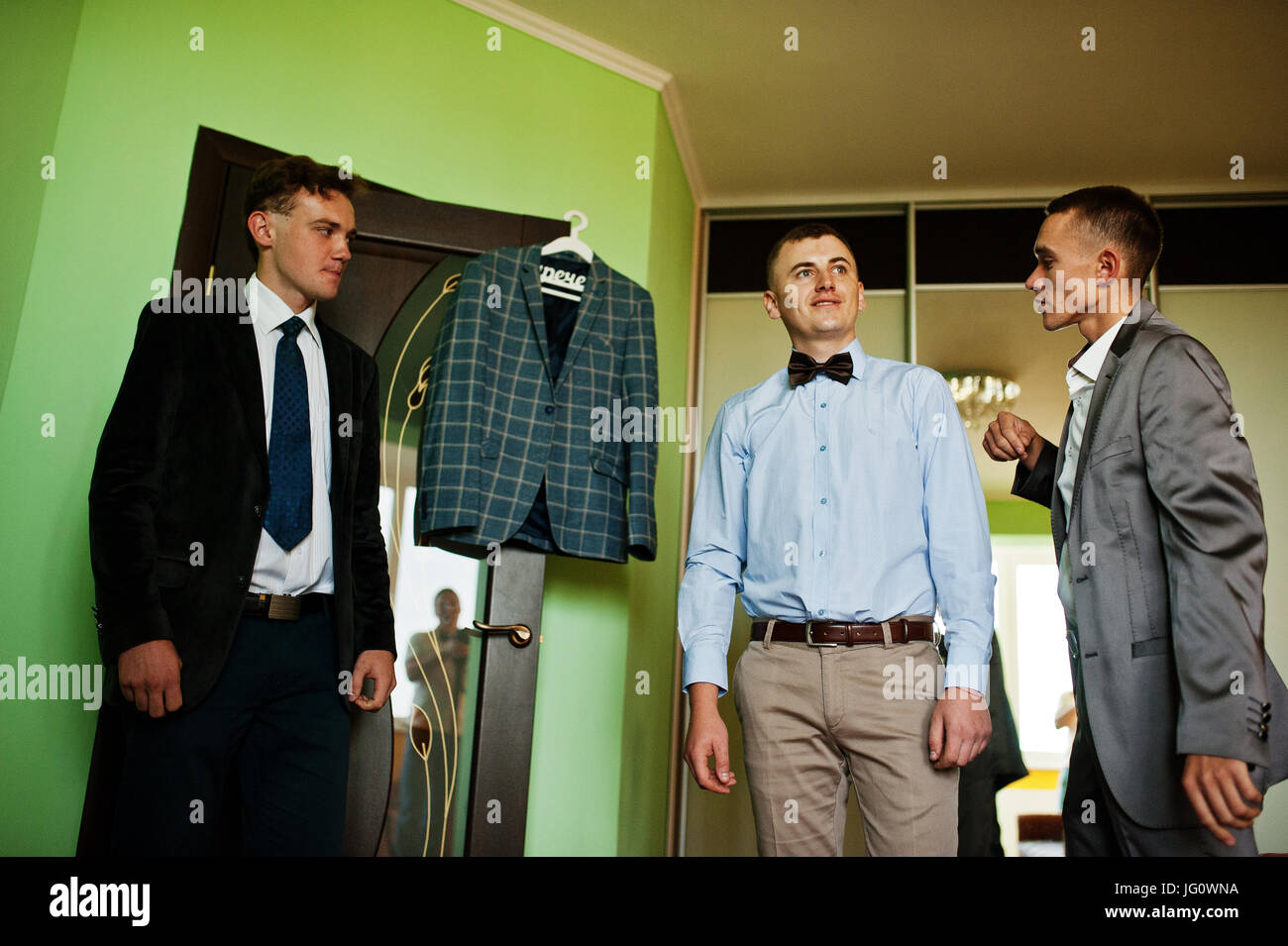 Groomsmen help a groom to get ready for his wedding in his room Stock ...