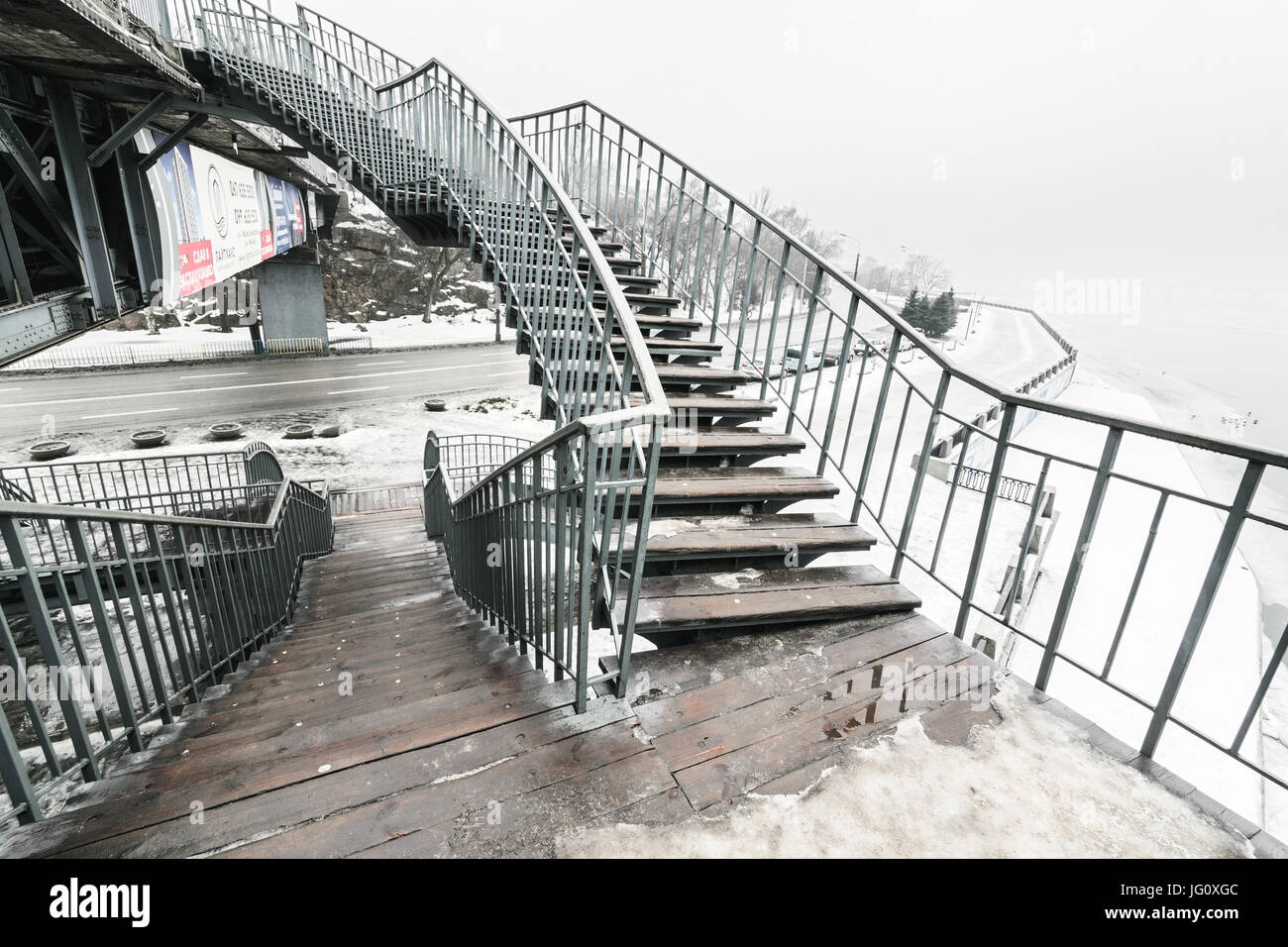 The steps of the stairs leading to the bridge in the early foggy winter ...