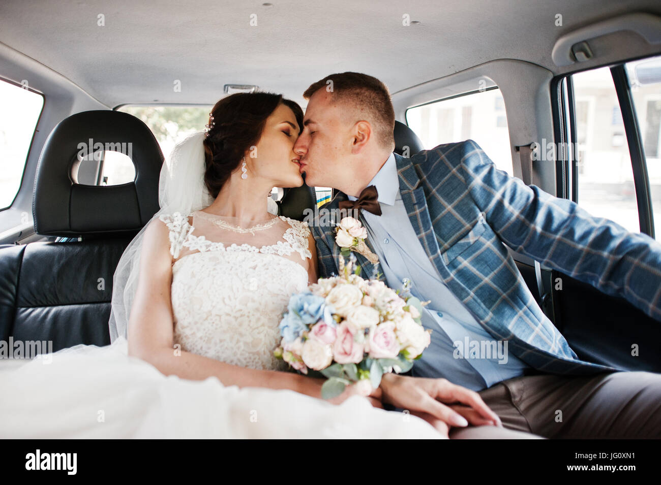 Gorgeous wedding couple kissing in a car Stock Photo - Alamy