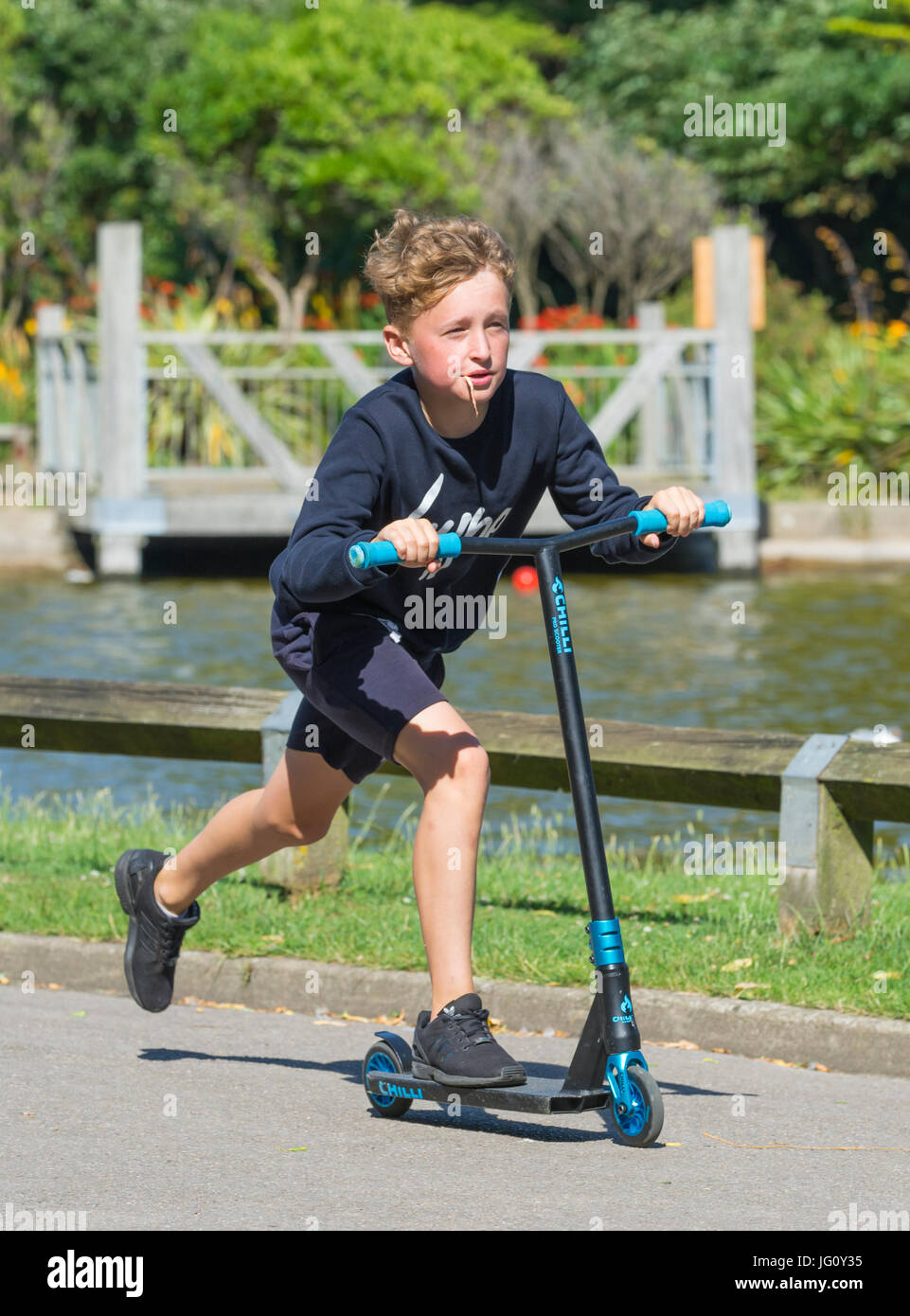 Young boy riding through a park on a scooter Stock Photo - Alamy