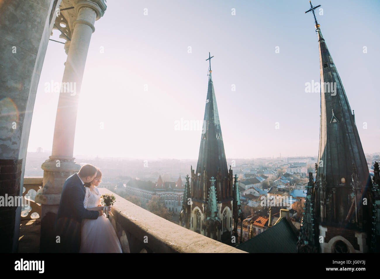 Happy newlyweds holding each other on the balcony of old gothic ...