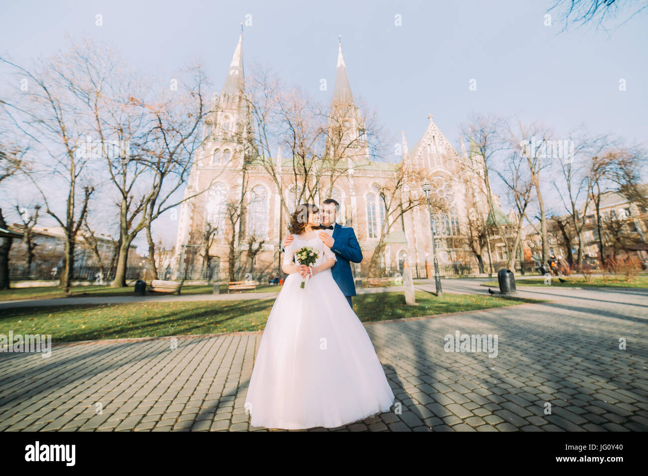 Horizontal view of the groom hugging the bride back in the front of the ...