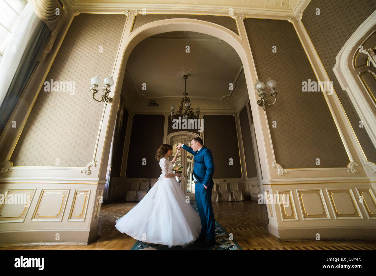 Horizontal view of the happy newlyweds dancing in the hall of the old ...