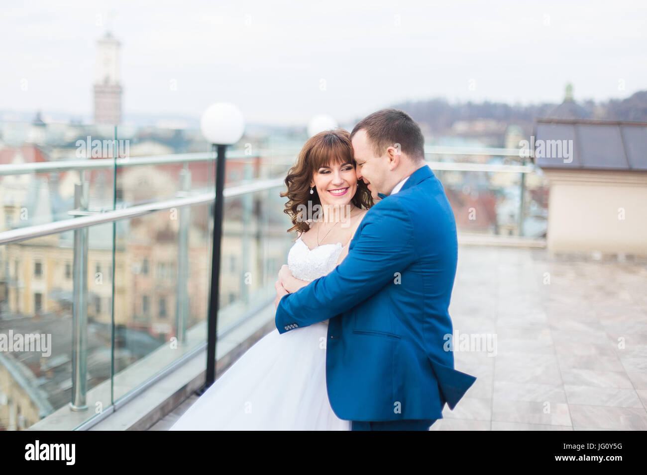 Emotional photo of the groom hugging the smiling bride back while ...