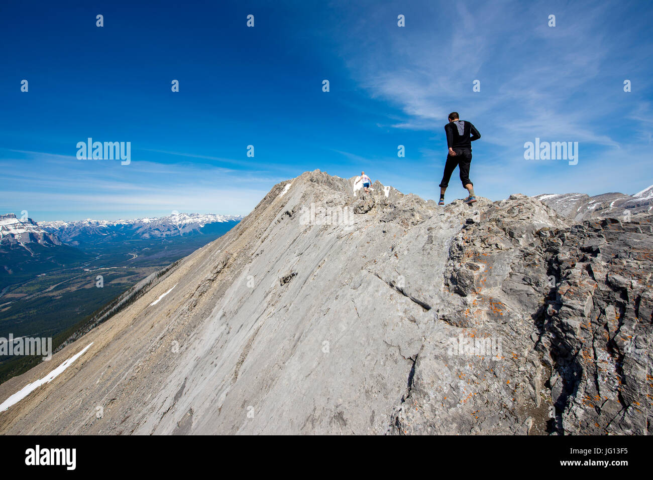 Two men trail running a steep ridge line in the mountains of canada ...