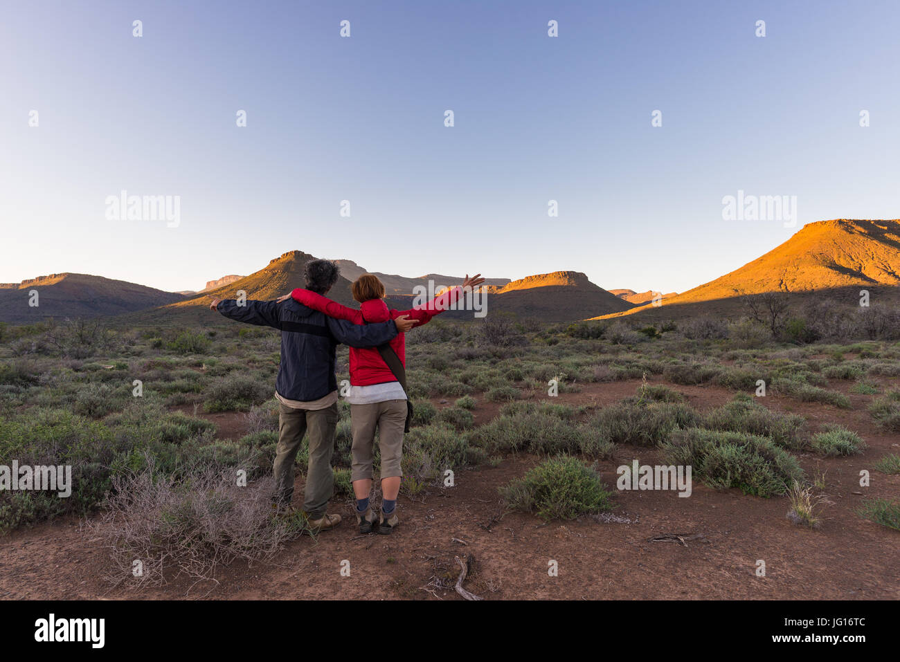 Hugging couple with outstretched arms watching the stunning view of the ...