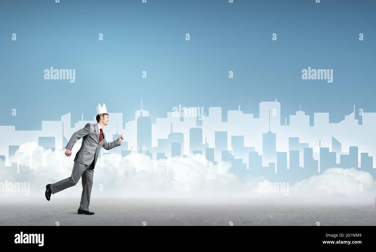 Young handsome businessman wearing white paper crown running in a hurry ...