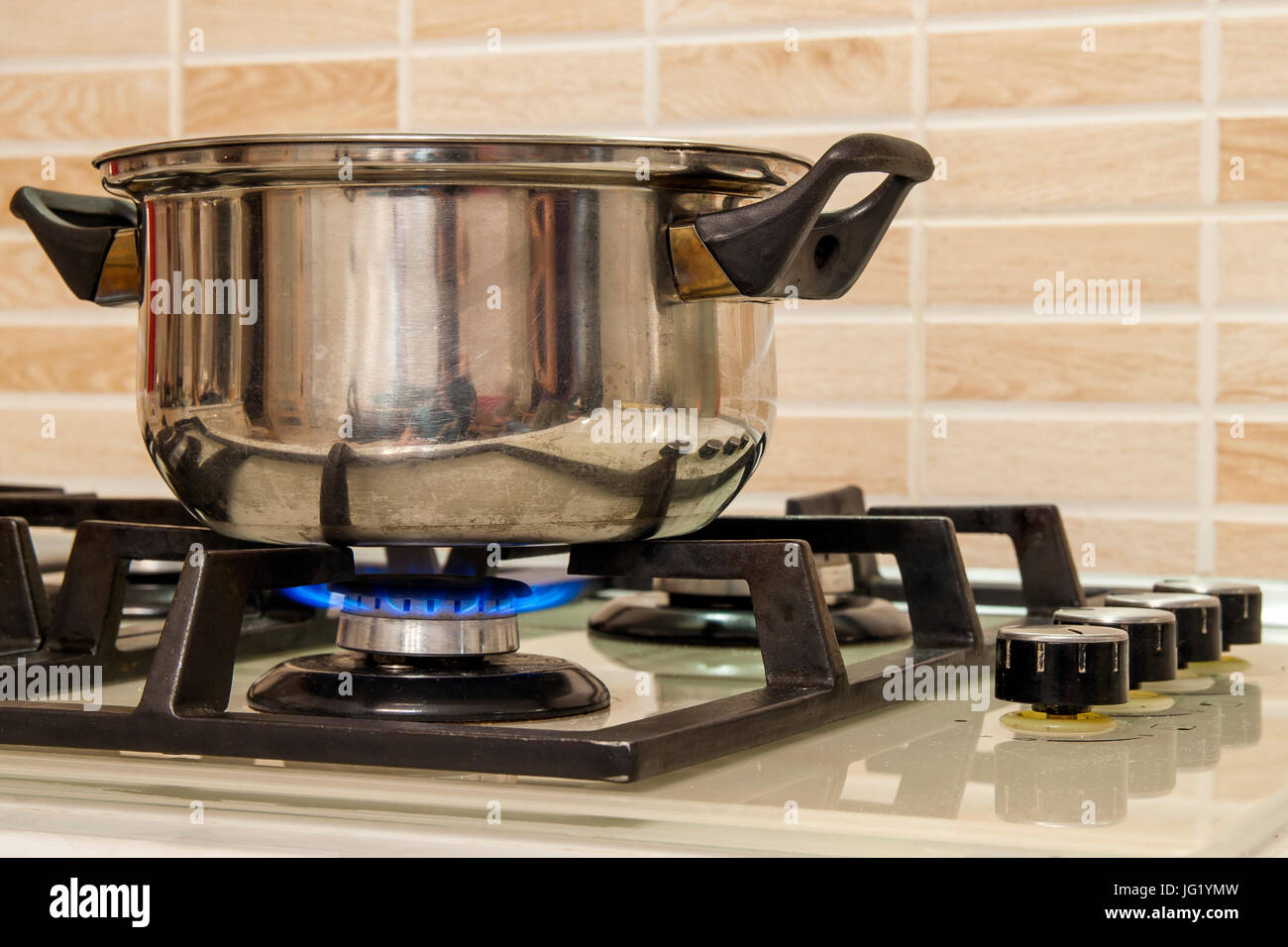 Metal cooking pot standing on kitchen stove with flame Stock Photo - Alamy