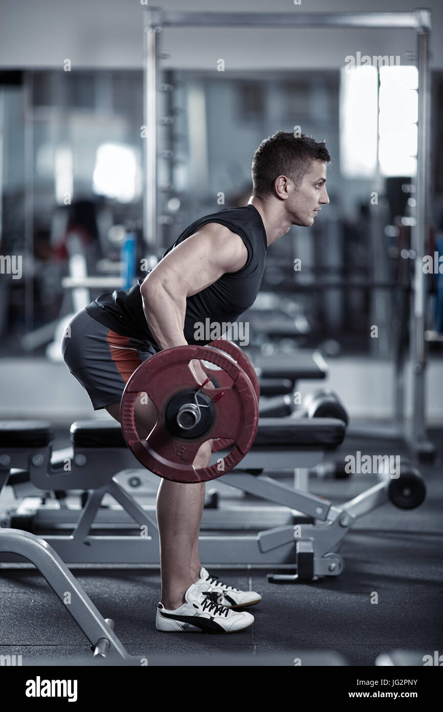 Young man doing barbell row in the gym Stock Photo - Alamy