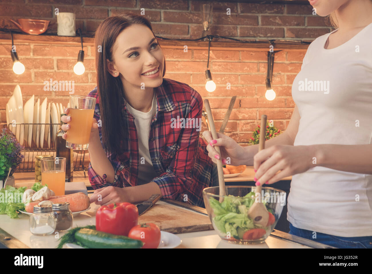 Young female friends cooking meal together at home mixing salad Stock ...