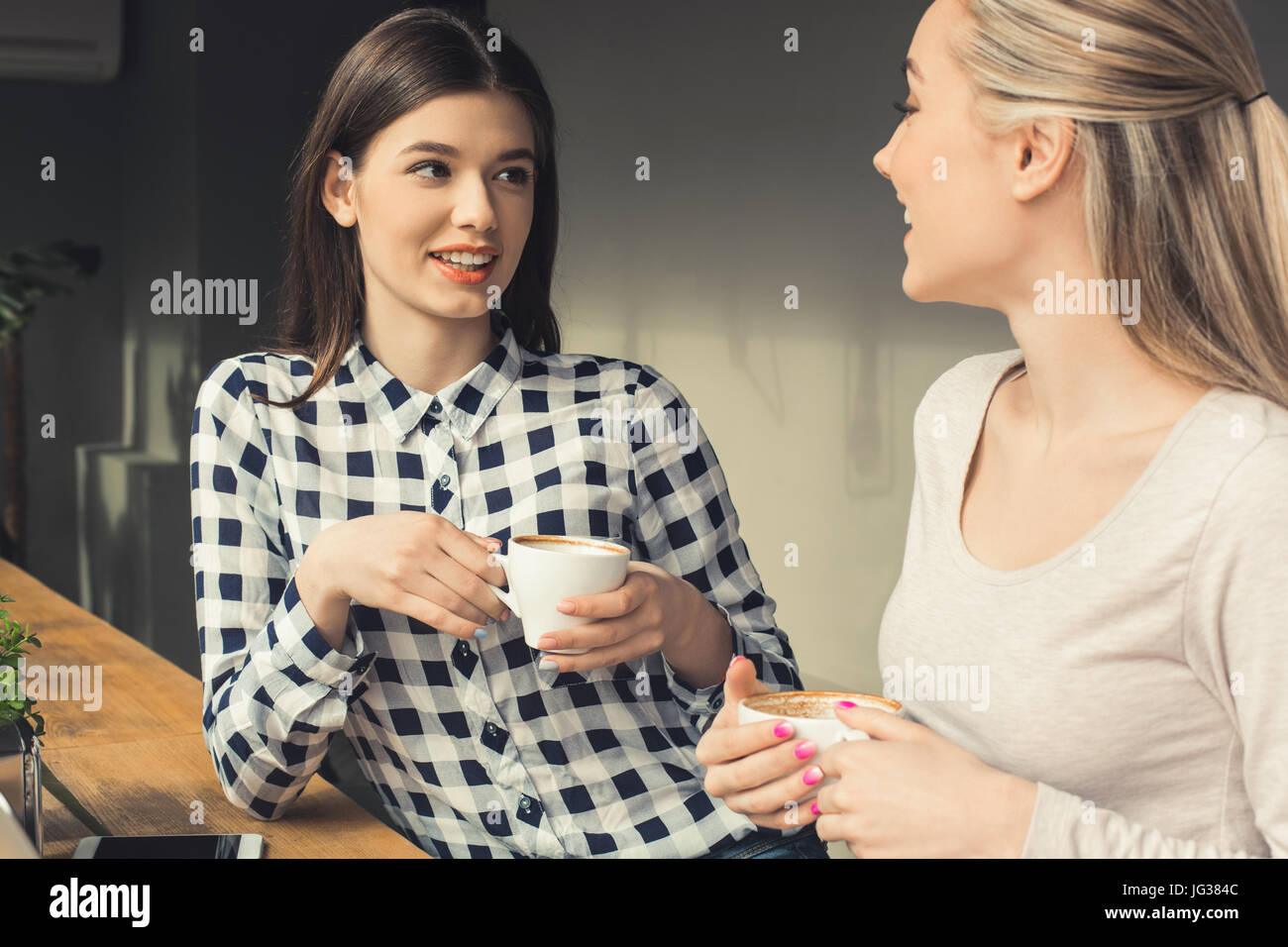 Young female friends in a coffee shop gossip Stock Photo - Alamy