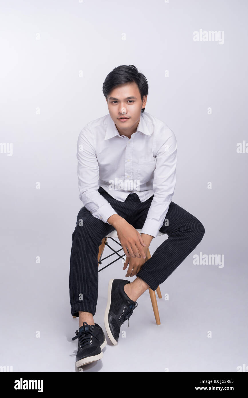Smart casual asian man seated on chair in studio background Stock Photo ...