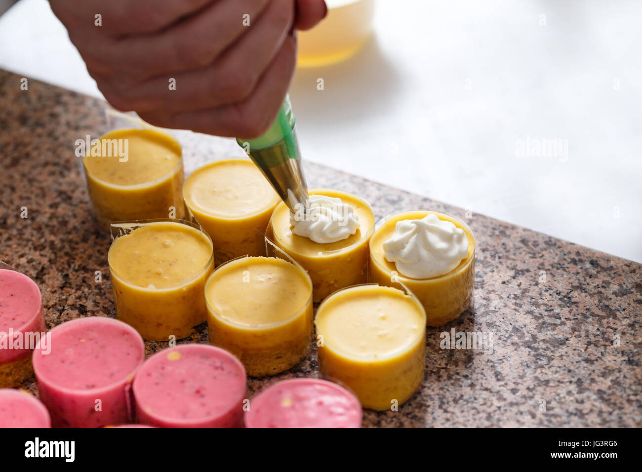 Woman hand decorating mini cakes with pastry cream Stock Photo - Alamy