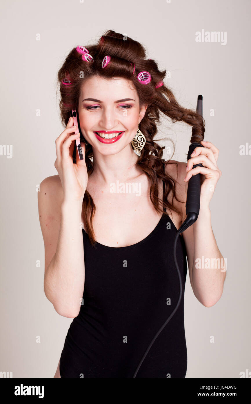 girl with hair curlers talking on the phone and makes the hairstyle ...