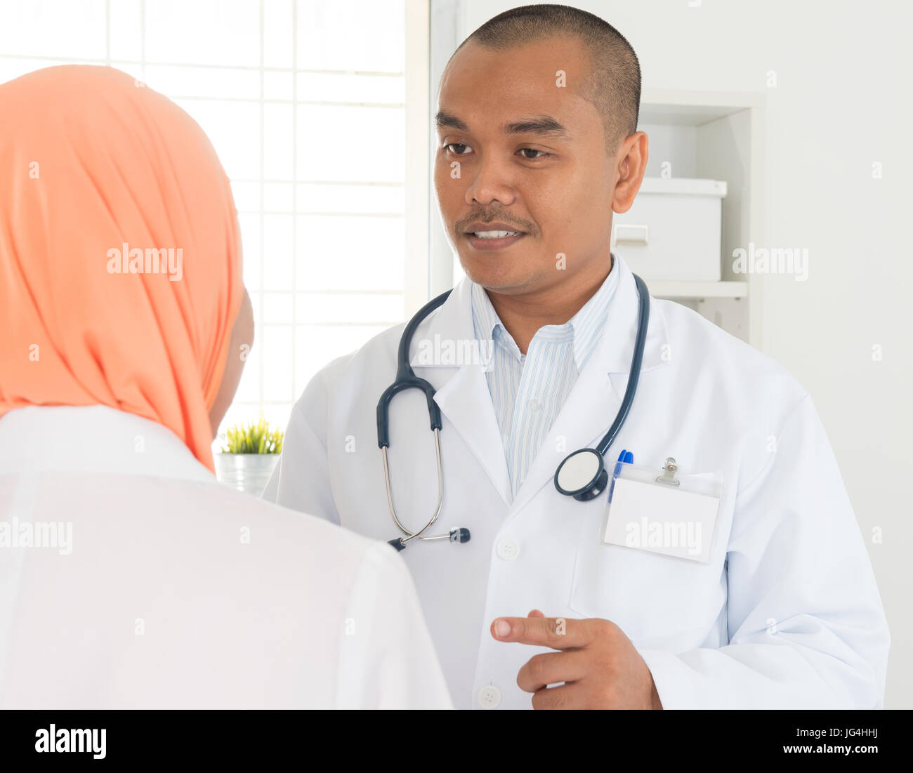 Male medical doctor talking with nurse inside hospital. Southeast Asian ...