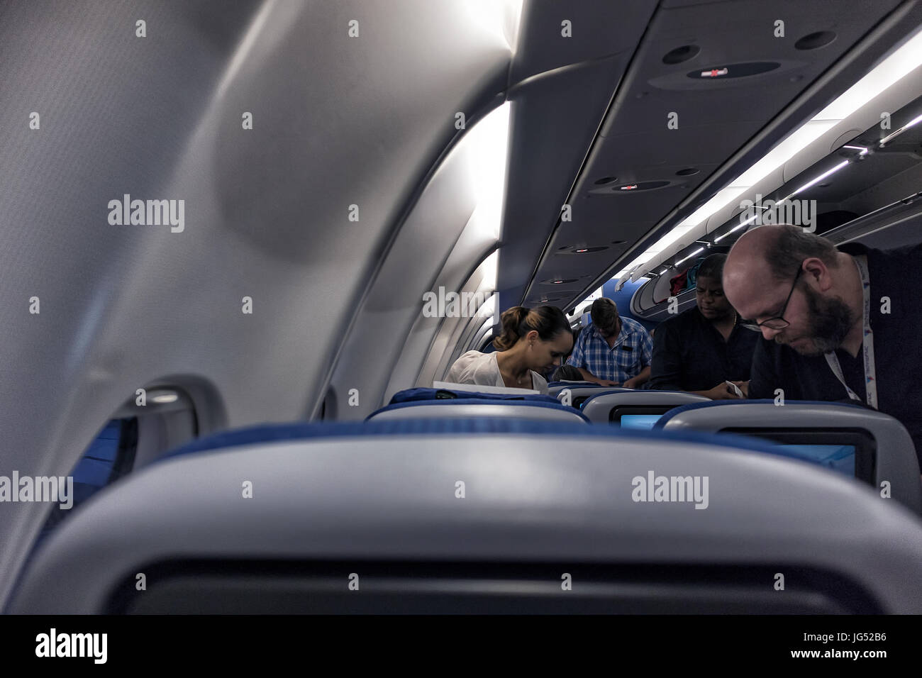 Inside view of airplane with people packing their bags Stock Photo - Alamy